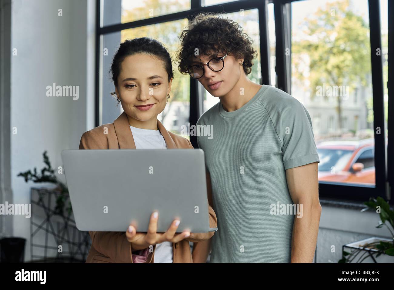 Two people collaborate around a laptop in a modern workspace ...