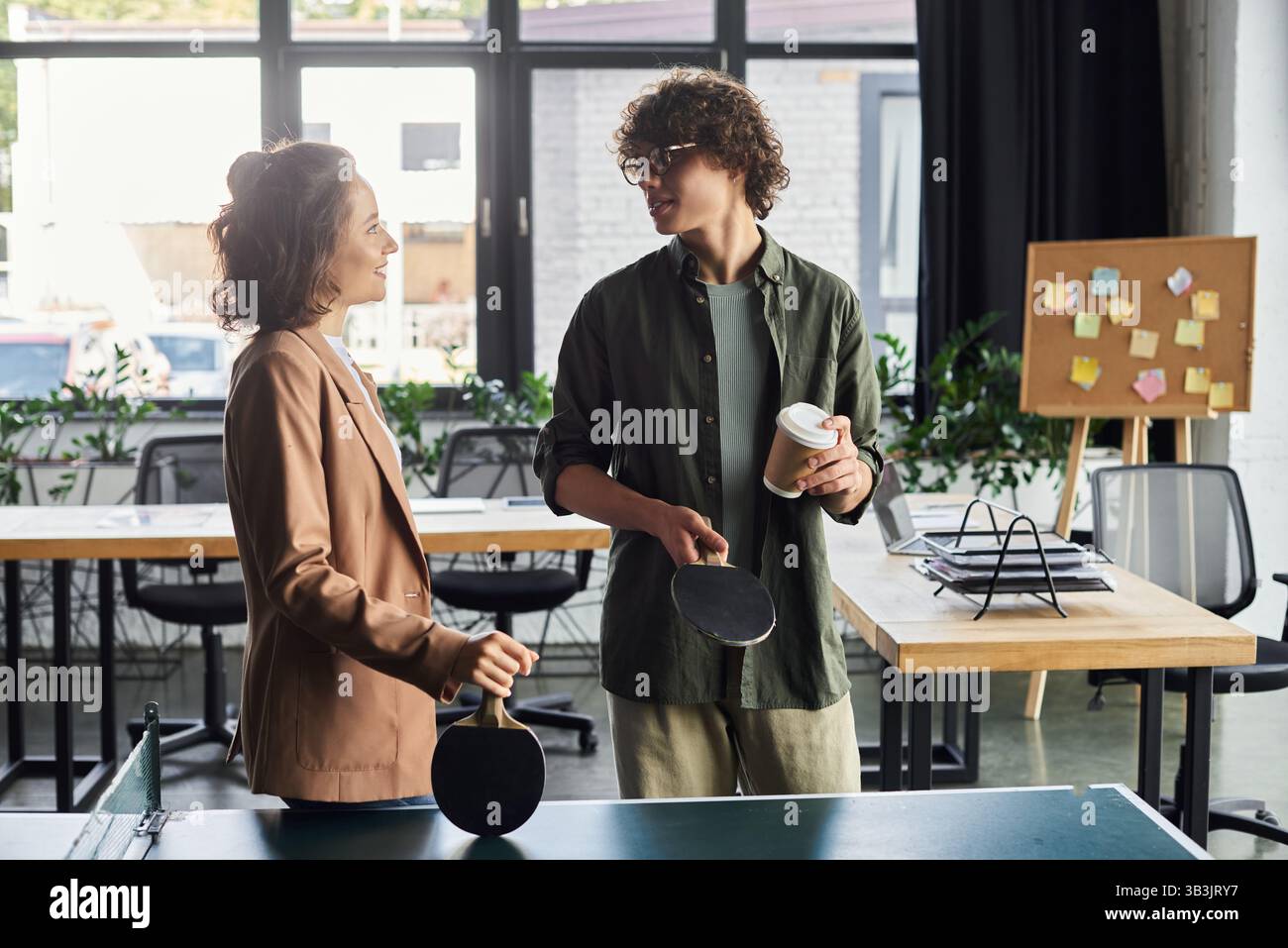 Two colleagues enjoy a lighthearted moment while playing table tennis ...