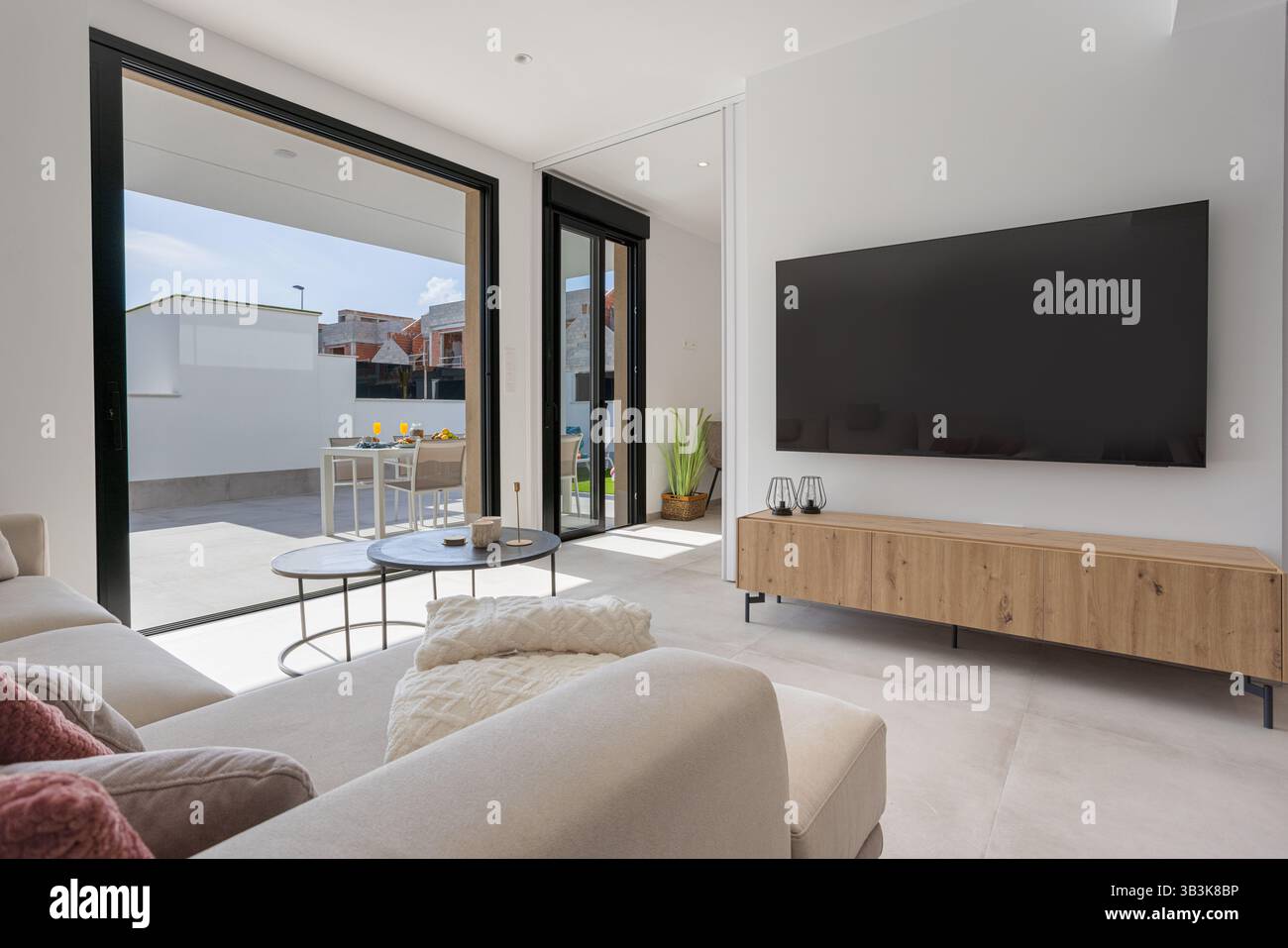 Neutral-toned lounge with a large TV and direct access to outdoor and ...