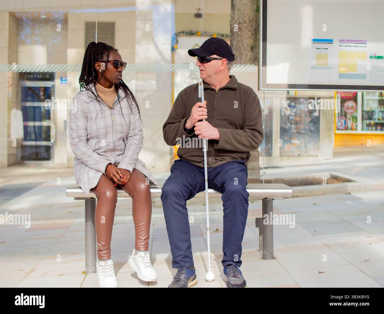 Blind man with a guide cane speaks with a woman at the bus stop Stock ...