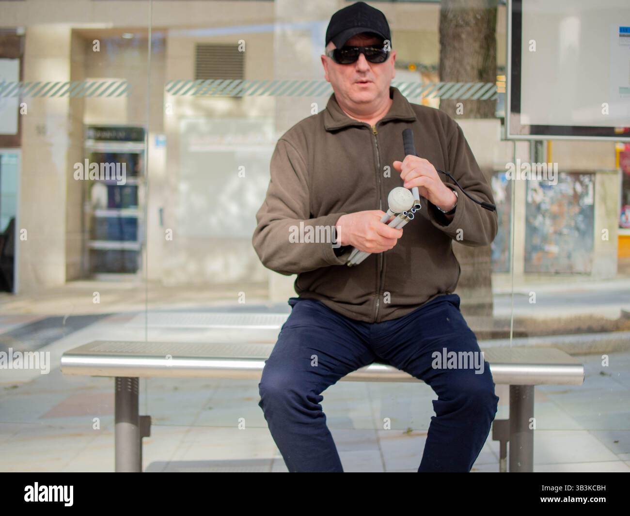 Sightless man folding his guide cane waits at the bus stop Stock Photo ...