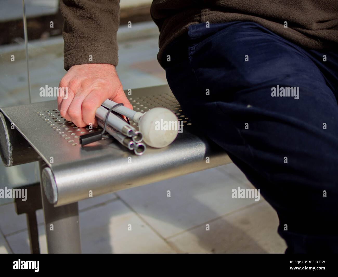 Blind man sits on bus stop bench with folded cane beside him Stock ...