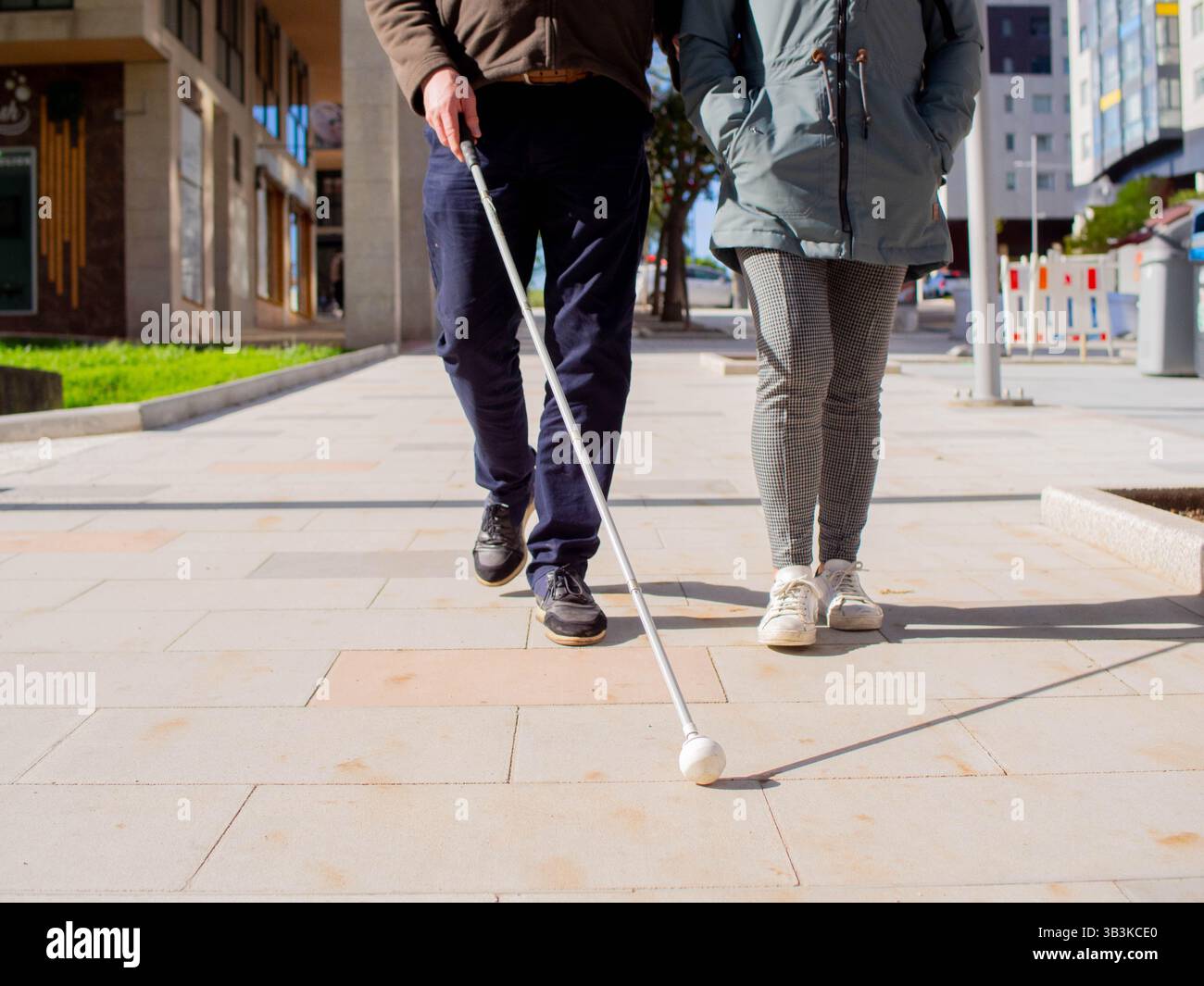 Front view of a sightless man walking on the pavement using his cane ...