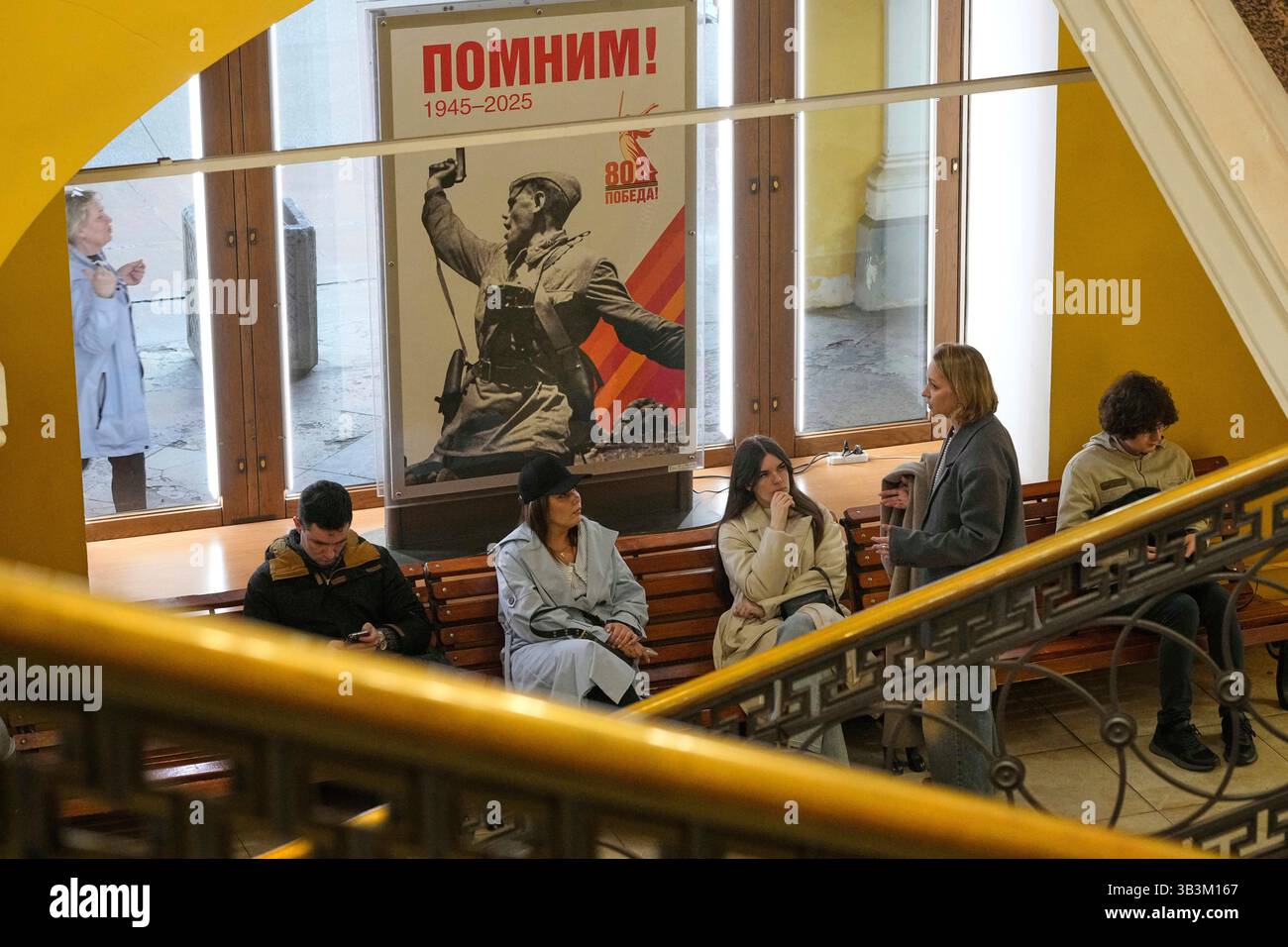 People sit in a shop next to a poster showing the photograph Kombat (a ...