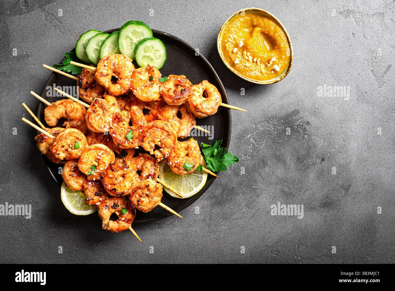 Grilled shimp prawn satay with spicy peanut sauce on dark concrete ...