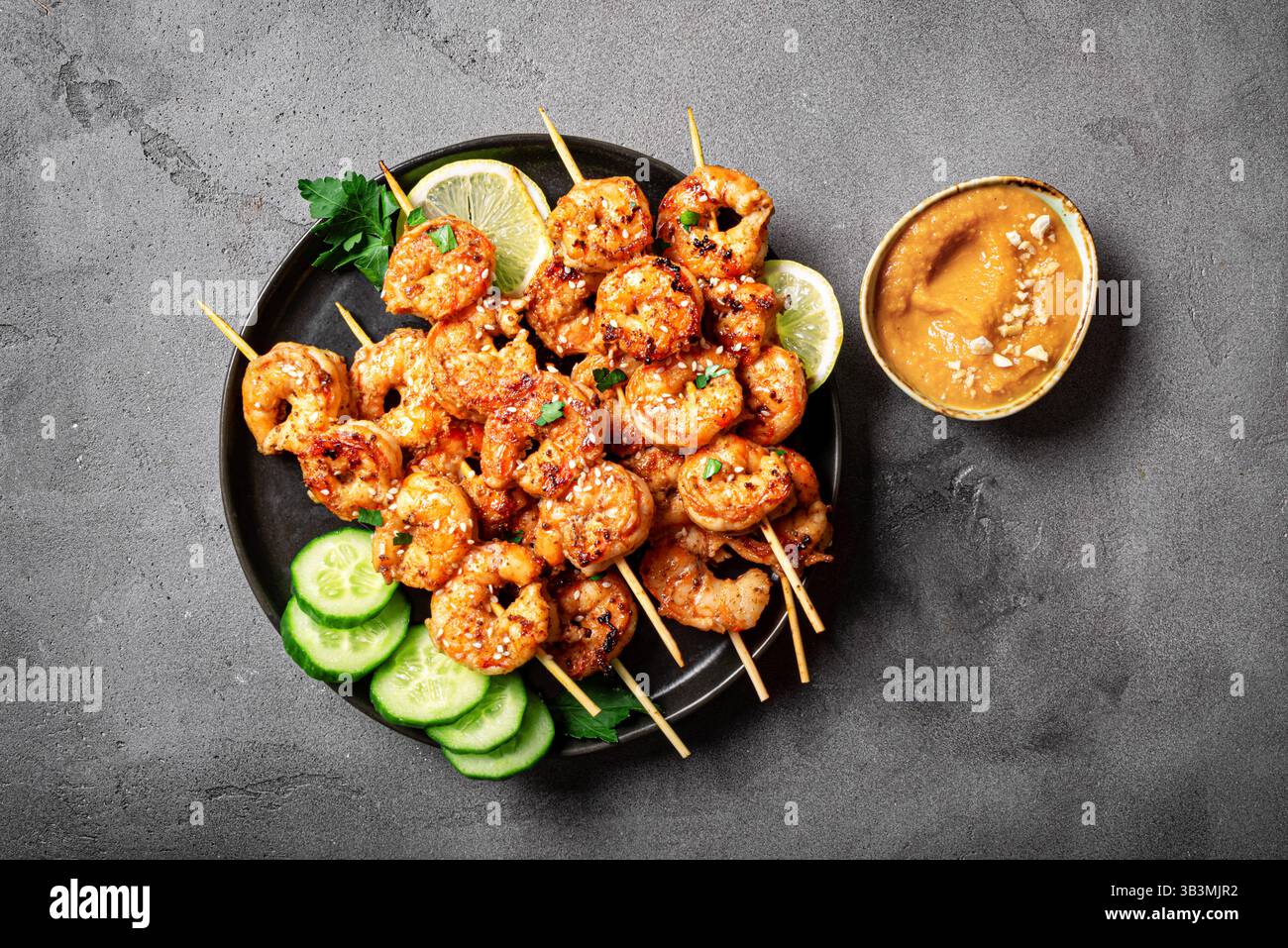 Grilled shimp prawn satay with peanut sauce on dark stone table, top ...