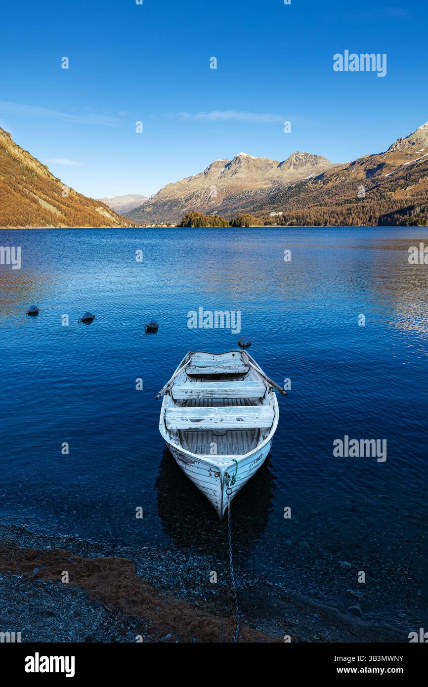 A lonely grundge rowing boat with docking chain at the blue lake side ...
