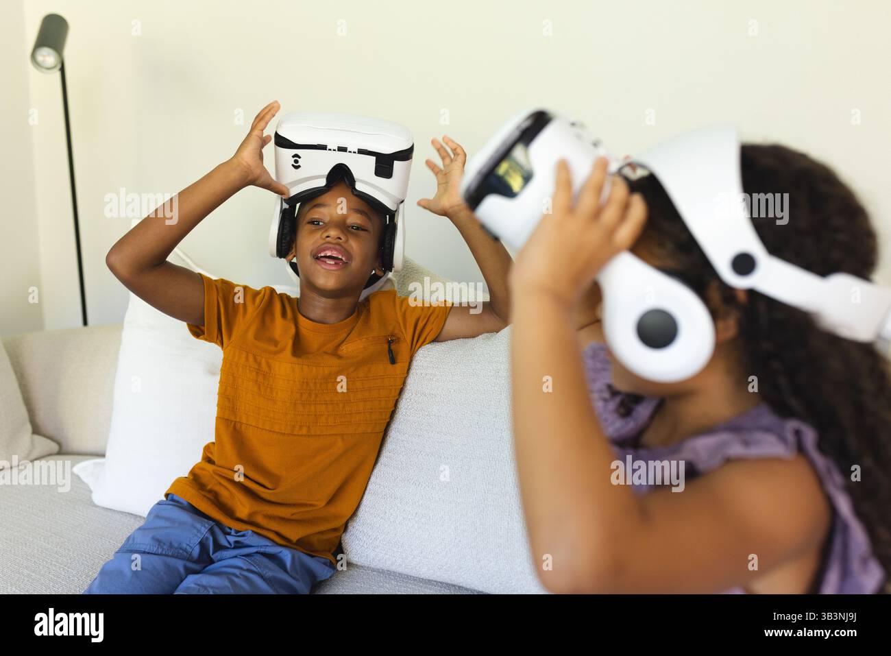Playing Diverse child siblings wearing white VR headsets on sofa in ...