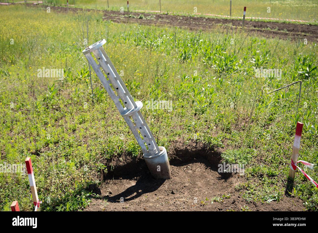 A cluster munition rocket sticks out of a farmer's field as deminers ...