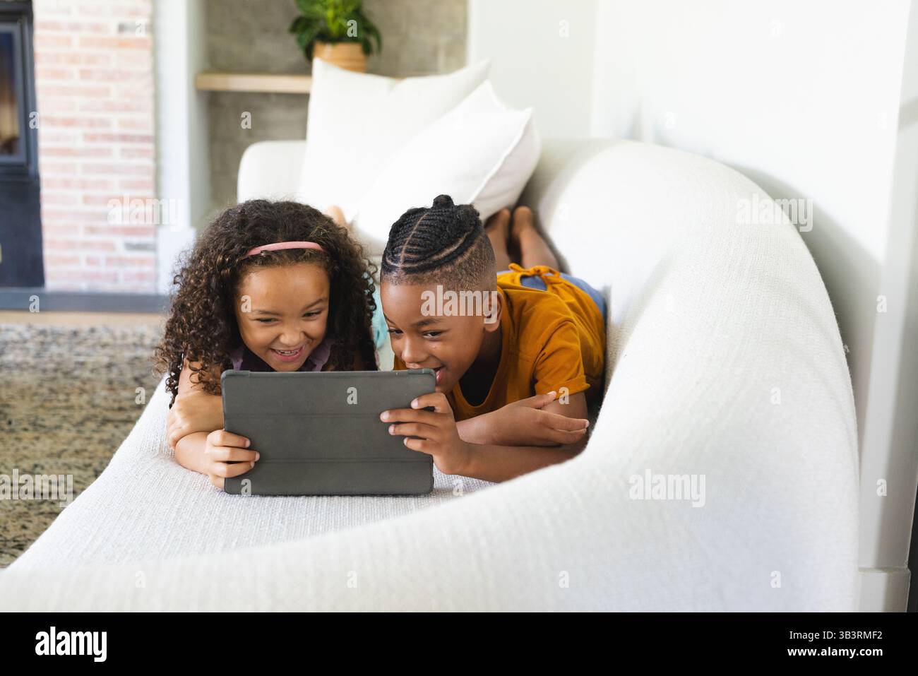 Lying diverse siblings leaning on couch in modern living room, with ...