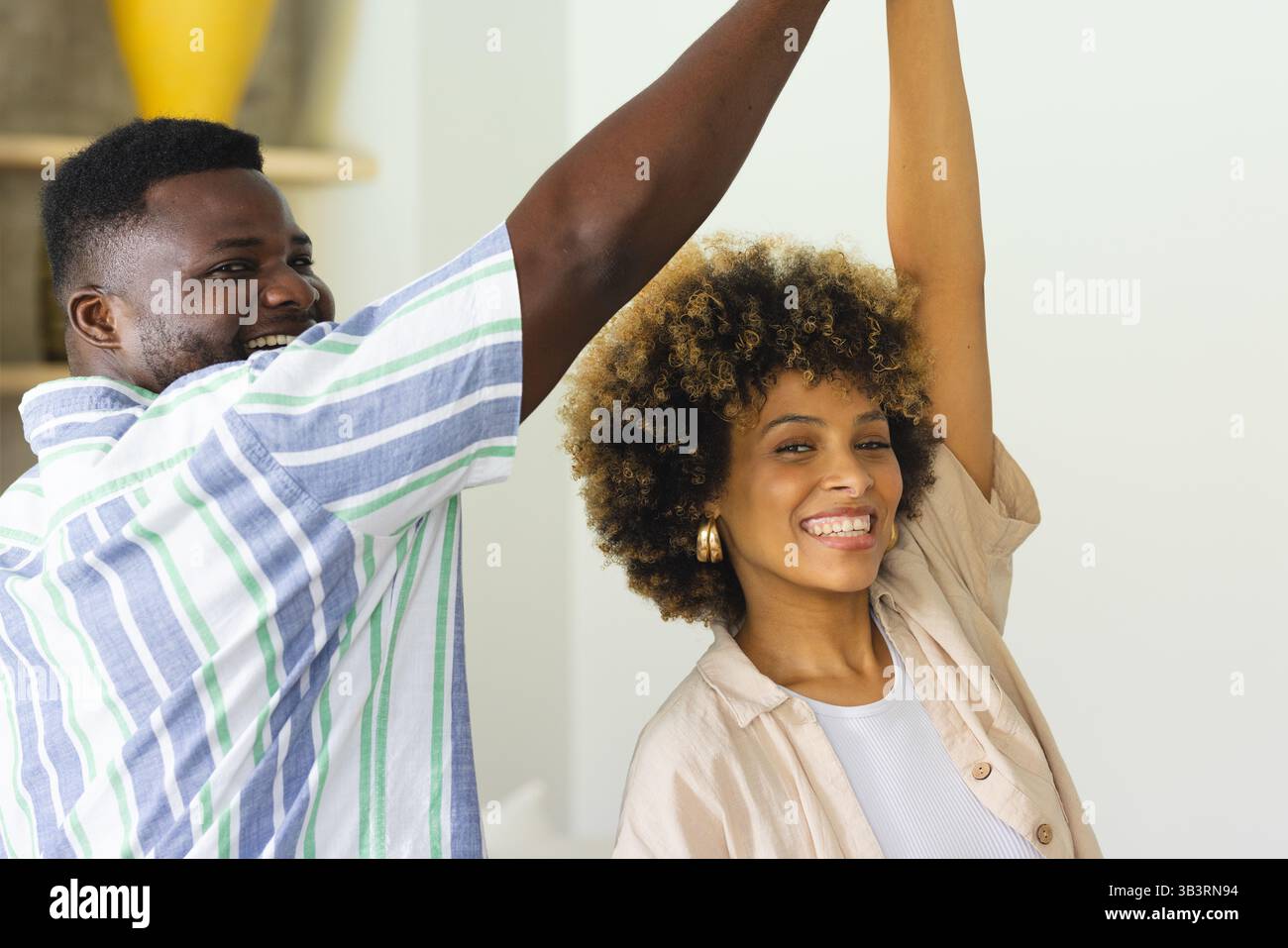 Dancing Diverse couple holding hands while spinning in living room ...