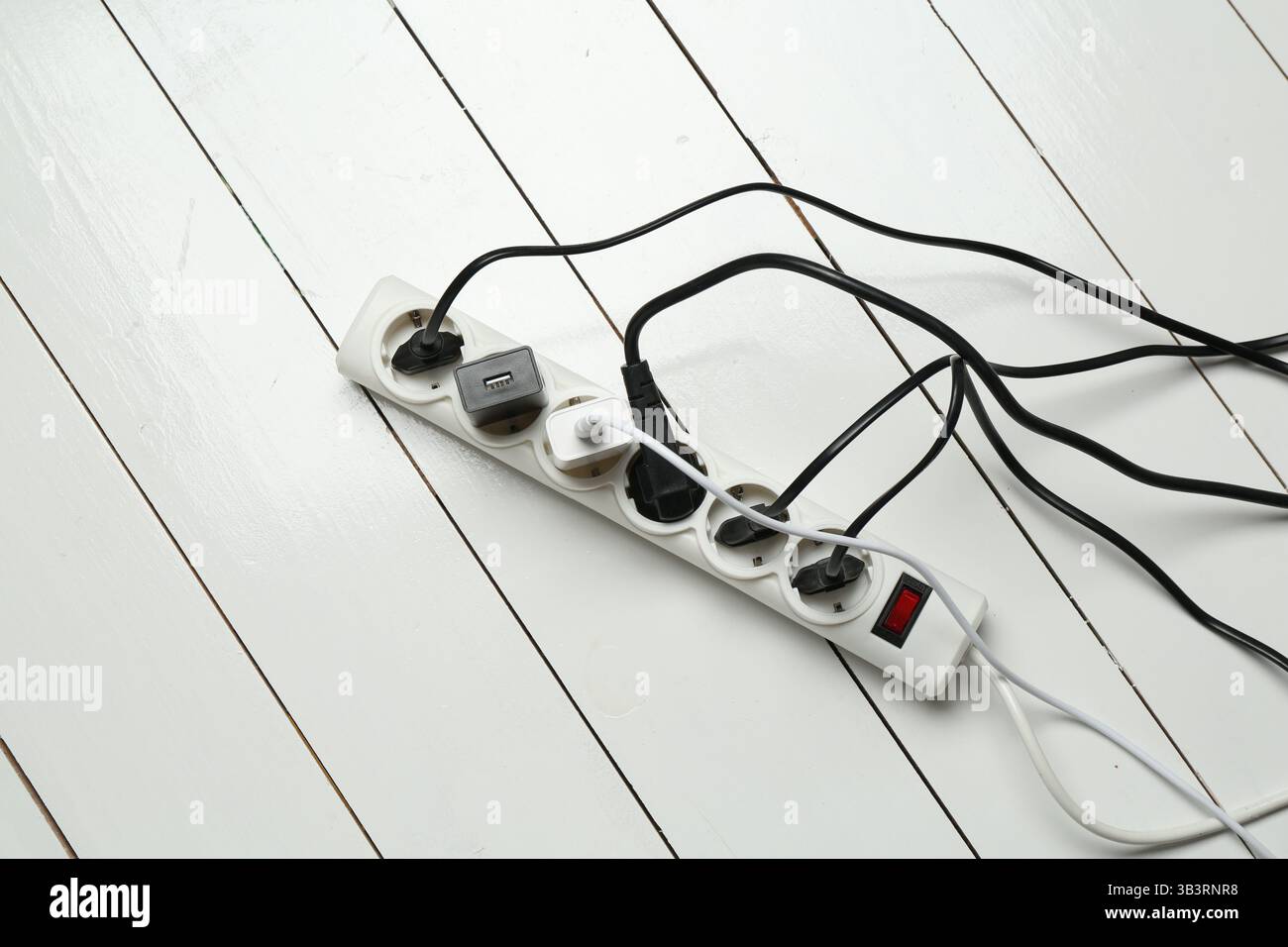 Extension power board overloaded with plugs on white wooden floor, top ...