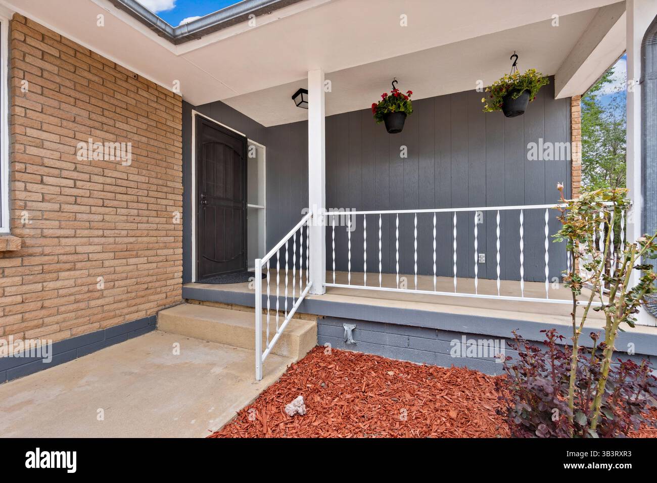 There stands a solid brick house that features a charming porch ...