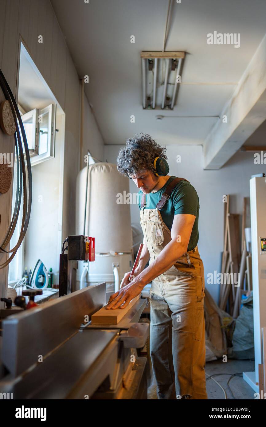 Skilled woodworker operate jointer machine, process wooden beam with ...