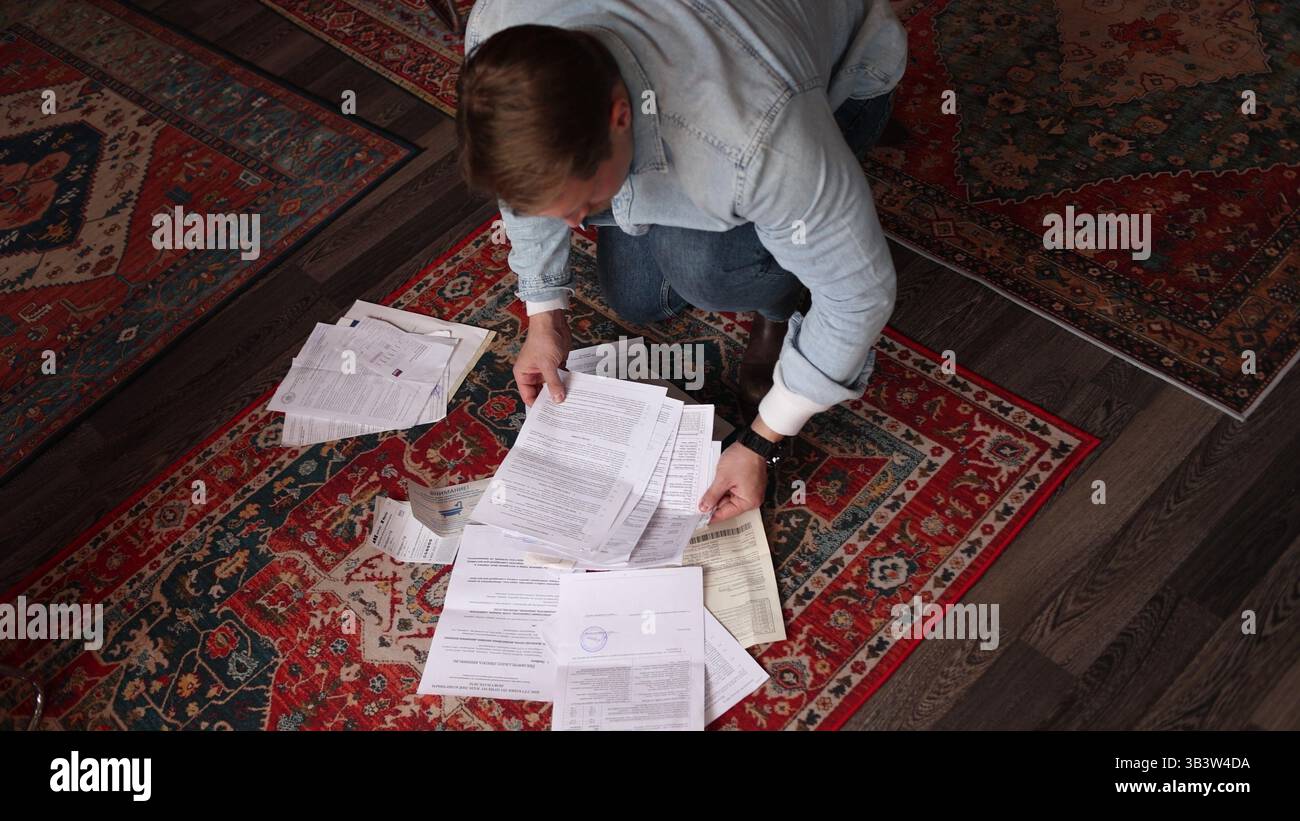Man intensely searches through paper stacks on floor, cinematic ...