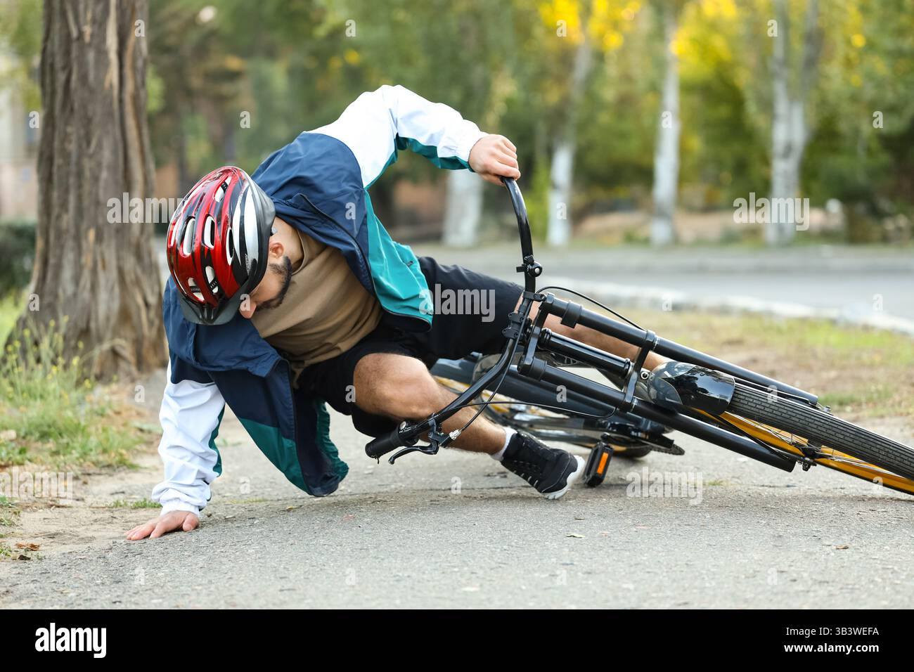 Young man getting up after falling off his bike outdoors Stock Photo ...