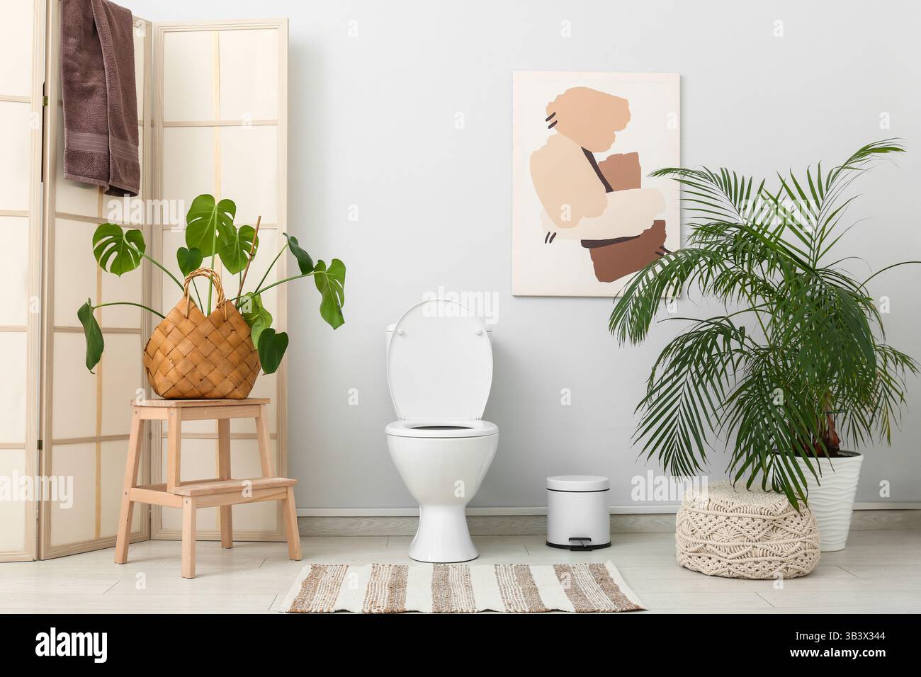 Interior of restroom with folding screen, toilet bowl and palm plants ...