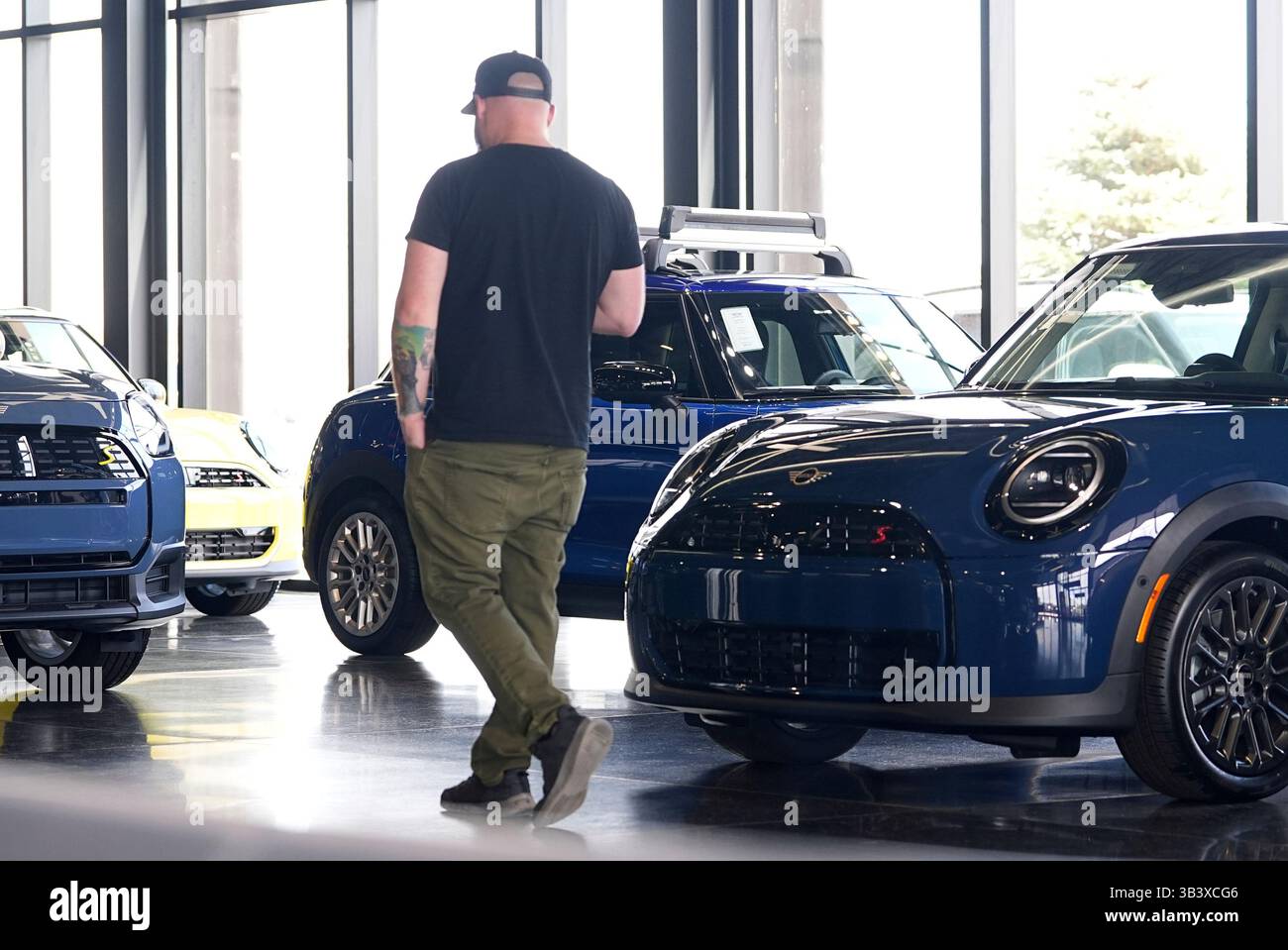 A customer wanders amid unsold 2025 Cooper hardtops on the showroom ...