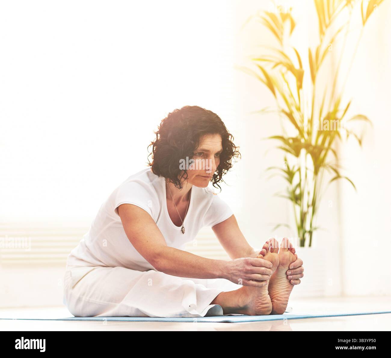 Mature woman doing yoga on a mat indoors. Health fitness yogi sitting ...