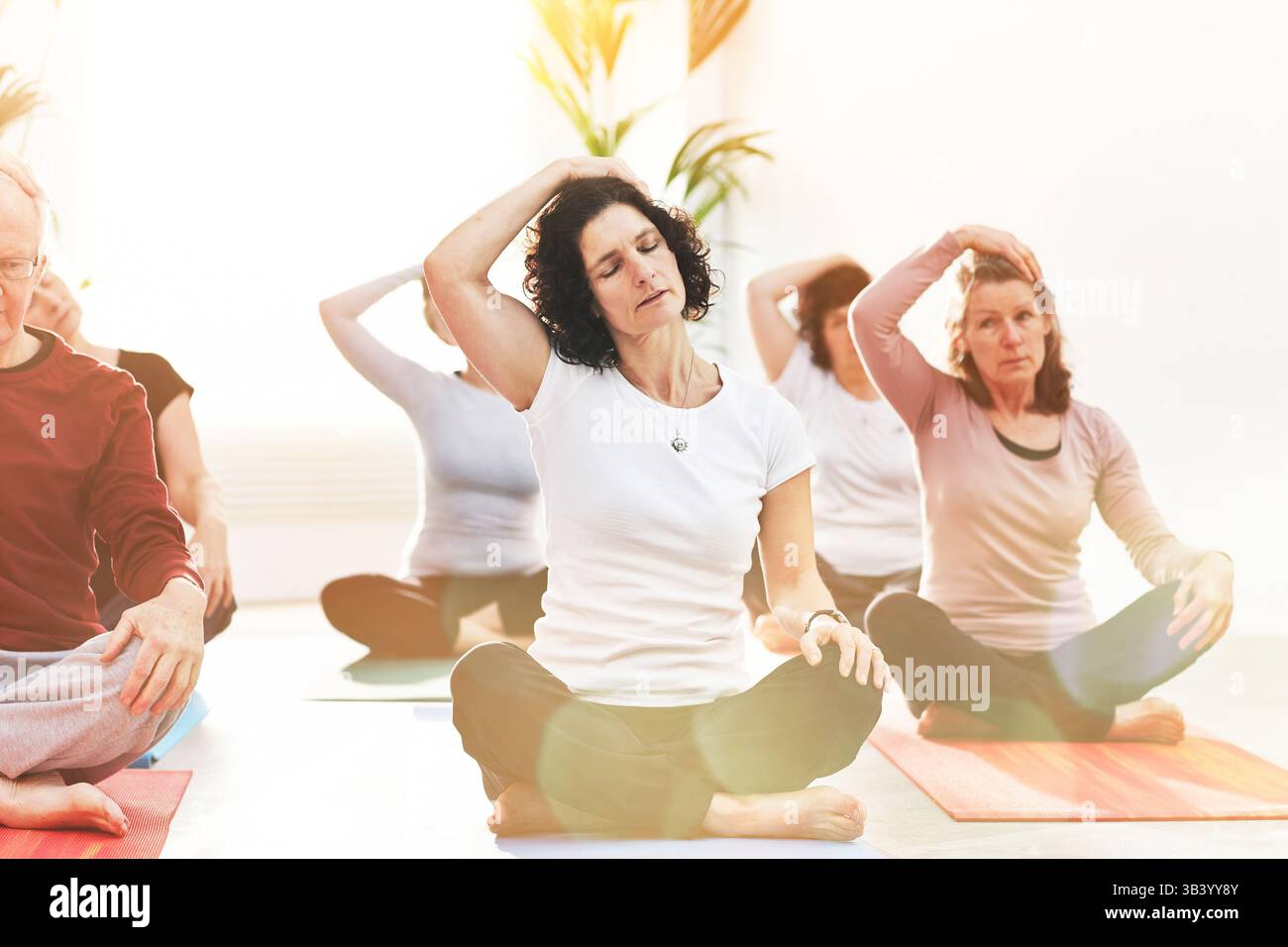 Yoga instructor training people with neck stretching exercises in lotus ...