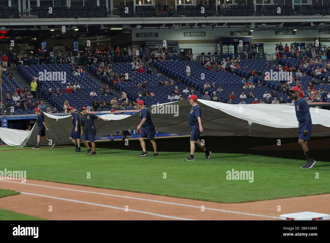 The grounds crew puts the tarp back on the field during a rain delay ...