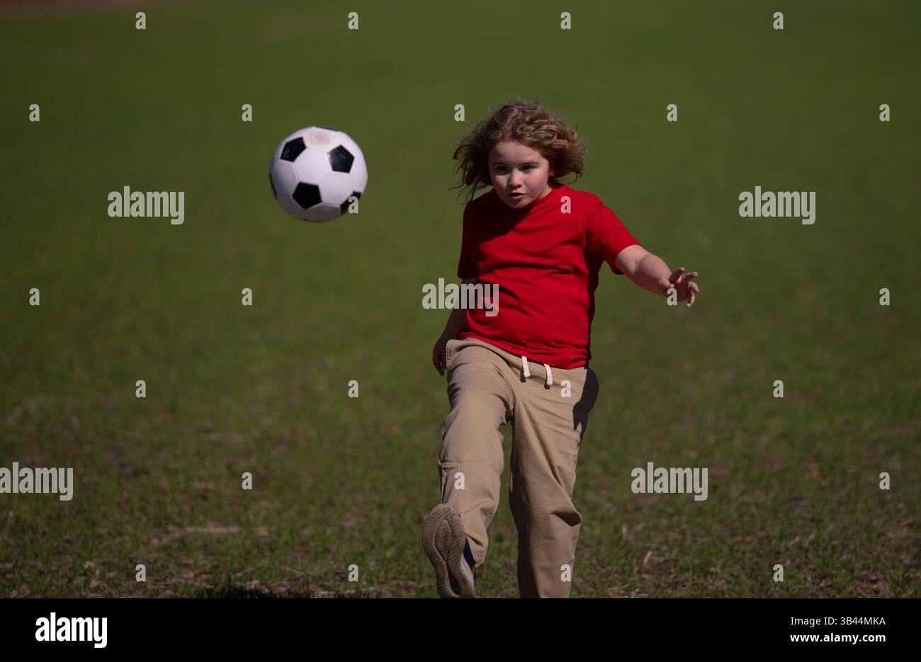 A kid is playing football. A child kicks the soccer ball. Kids sport ...