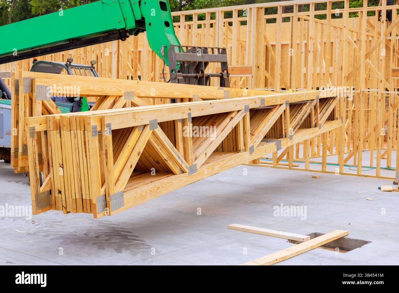 Telehandler crane raises wooden trusses at construction site during ...