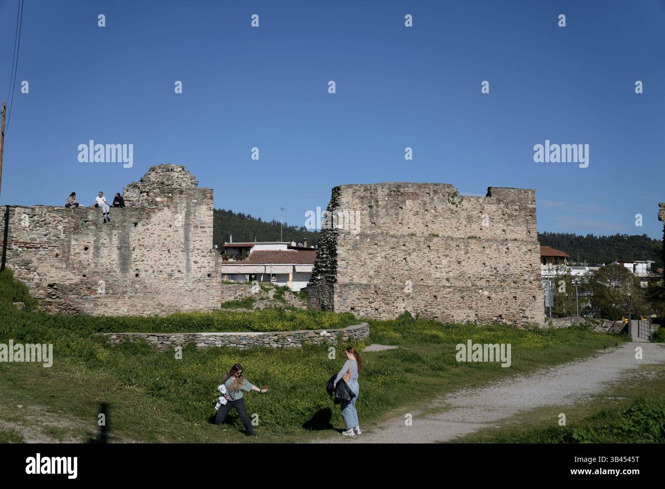 A girl holds a flower as people sit on a wall outside Yedi Kule prison ...
