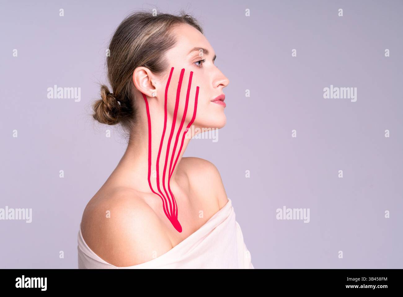 Woman in profile with red tape lines on face and neck on neutral ...
