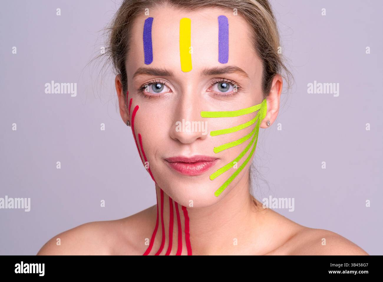 European woman applying medical tapes to face and neck, demonstrating ...