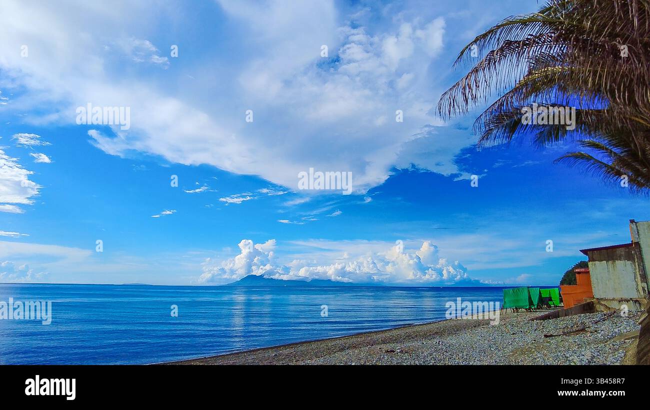 Tropical pebble beach on a bright blue sunny day. Fluffy white clouds ...