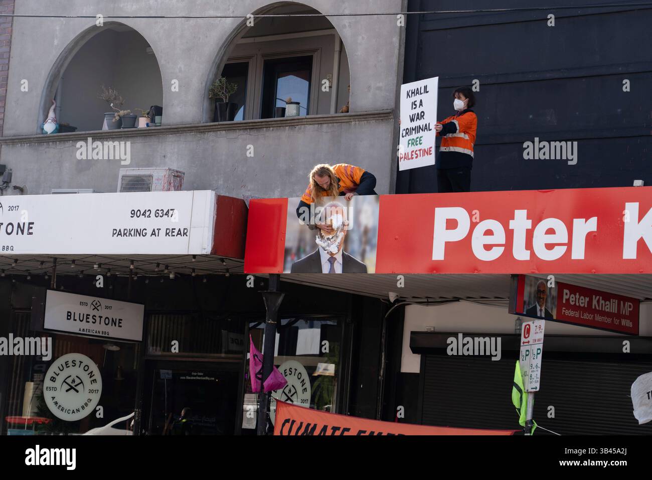 A protester cleans an image of Peter Khalil at his office. Pro ...