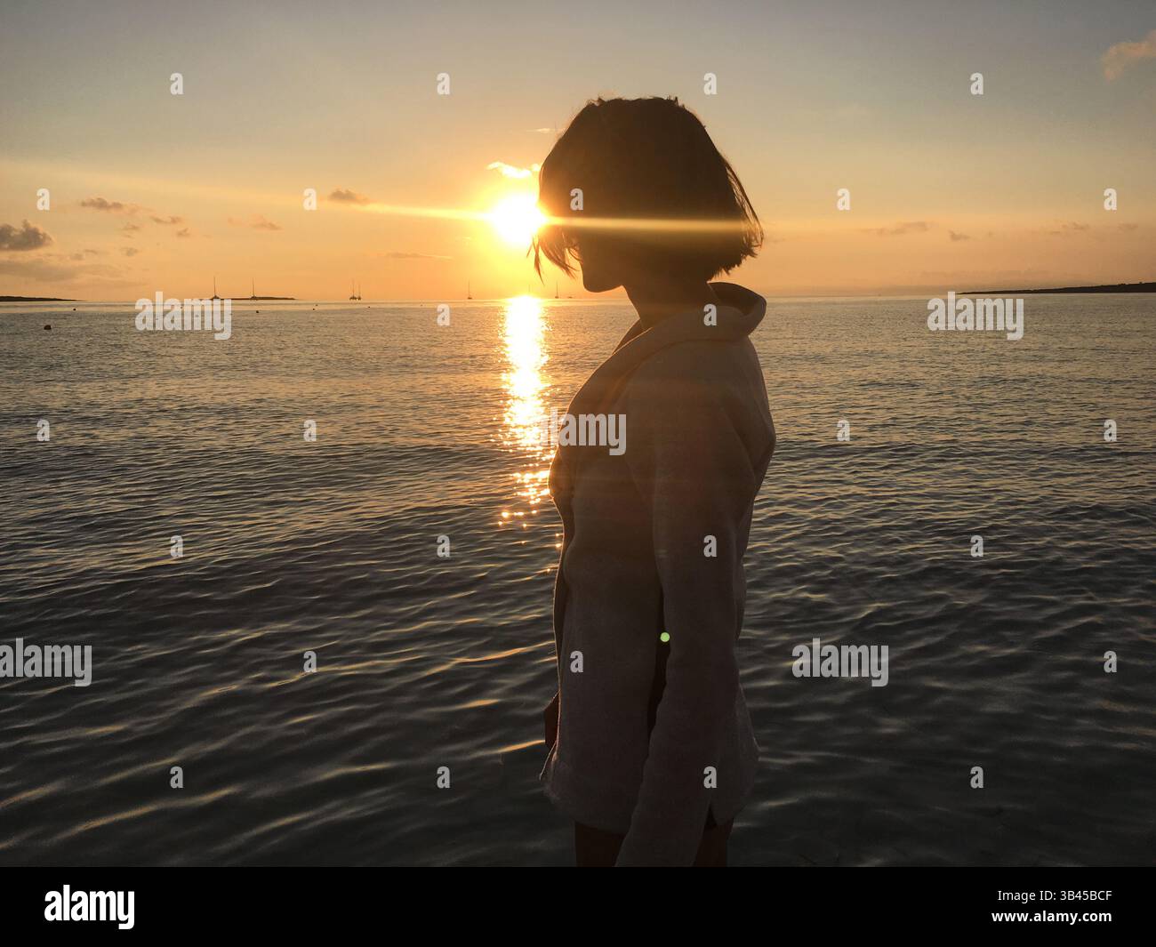 Unrecognisable woman silhouette watching the sun going up over the sea ...