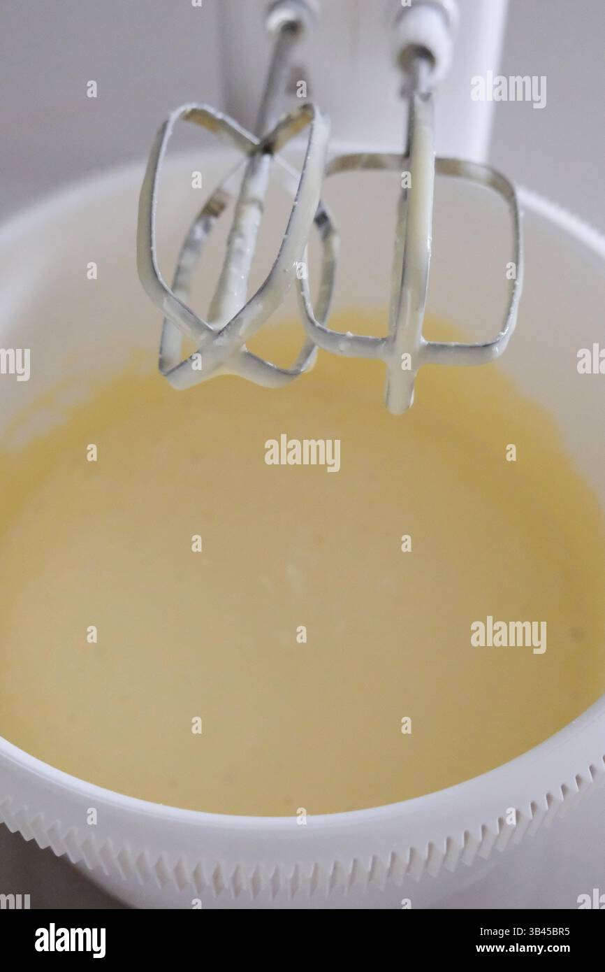 Preparation of dough mixture over a bowl with moving mixer, eggs, milk ...