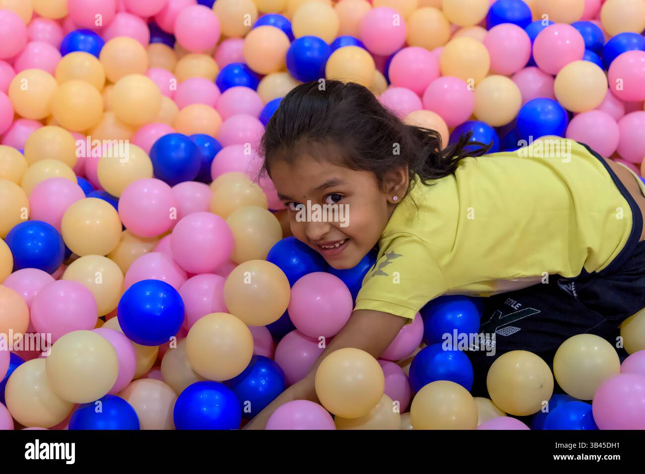 A joyful child explores a vibrant ball pit filled with colorful balls ...