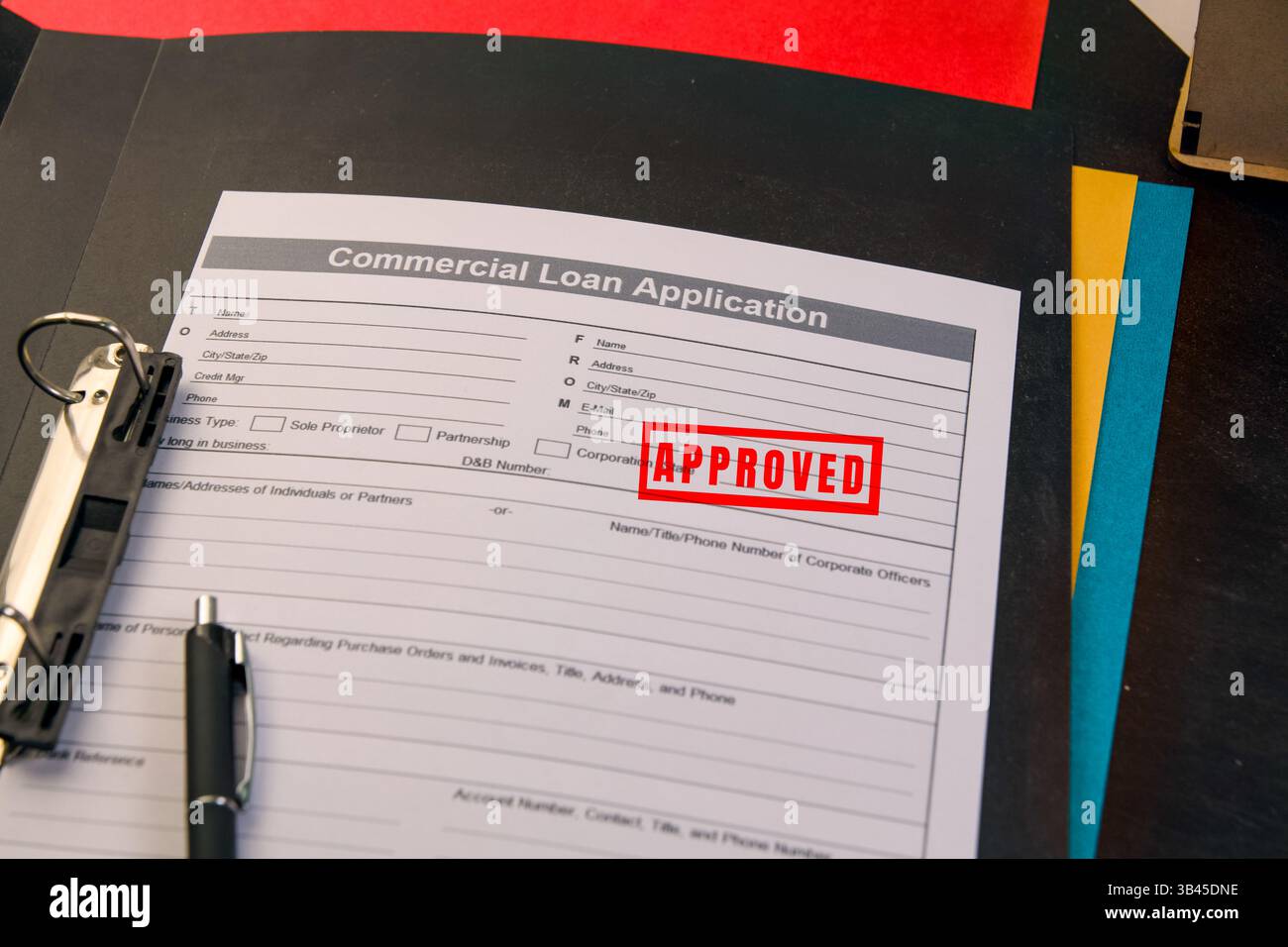 A completed commercial loan application is stamped approved and placed ...