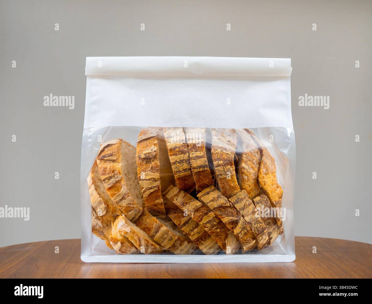 Sliced sourdough bread in white kraft paper bag with clear plastic ...