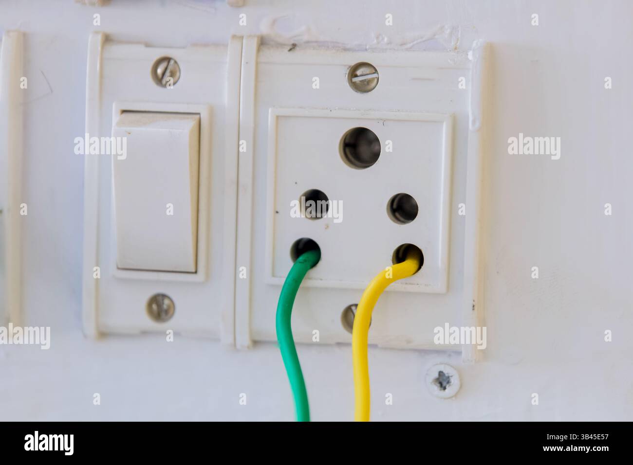 Colorful green and yellow wires connect to an electrical socket near a ...