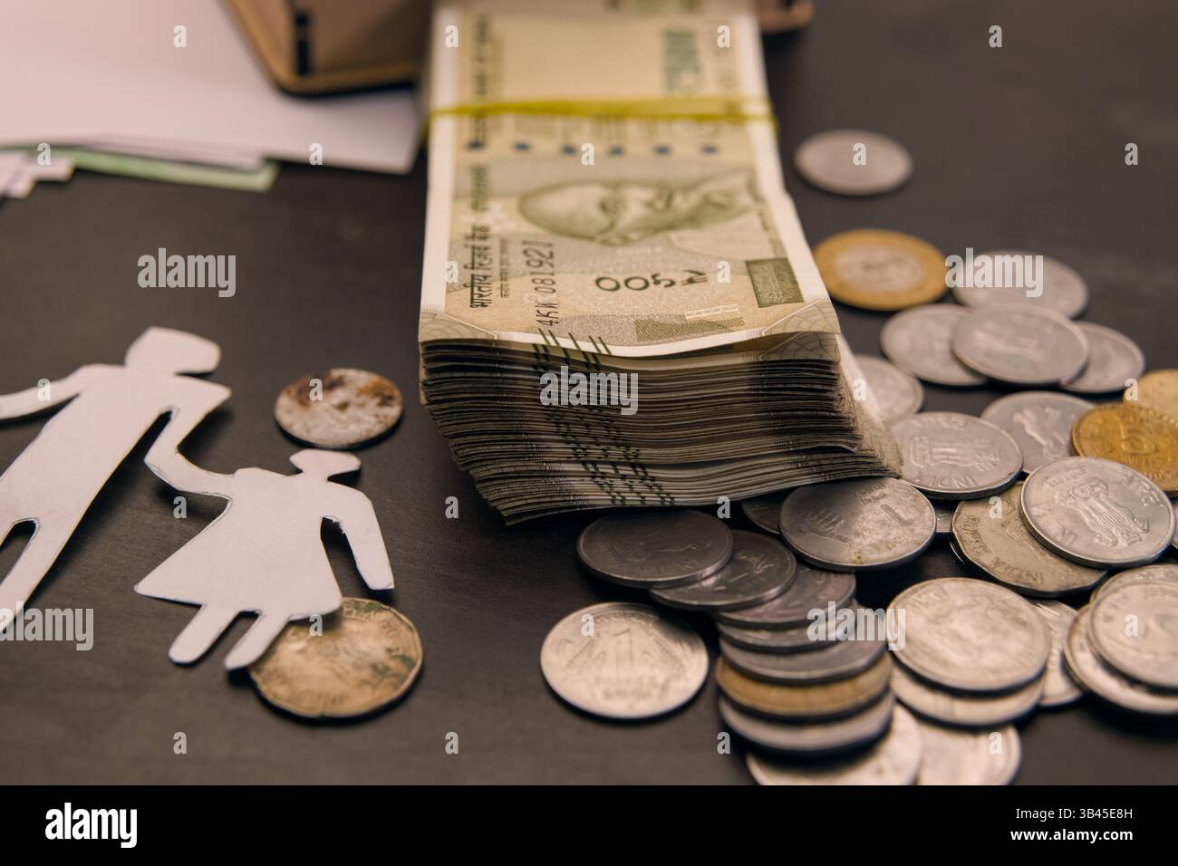 Paper family figures next to cash and coins represent financial ...