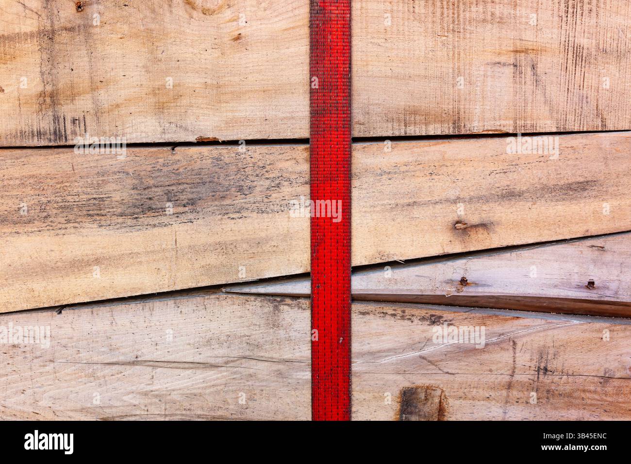 Wooden blocks are folded and tied with a red cargo strap in the middle ...