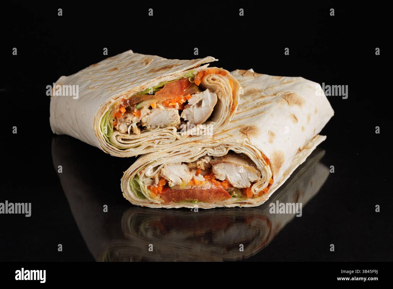 Freshly made chicken shawarma wrap cut in half, filled with grilled ...