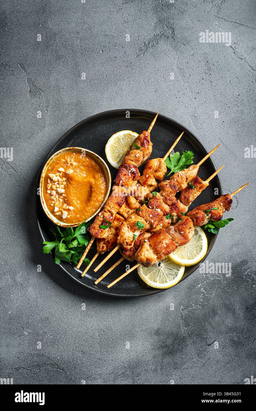 Grilled chicken satay with spicy peanut sauce on dark concrete table ...