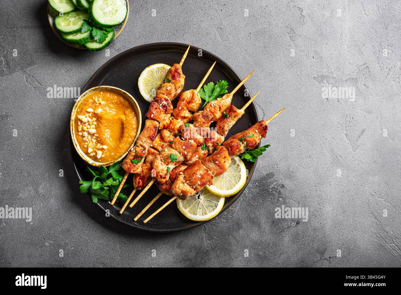 Grilled chicken satay with spicy peanut sauce on dark concrete table ...
