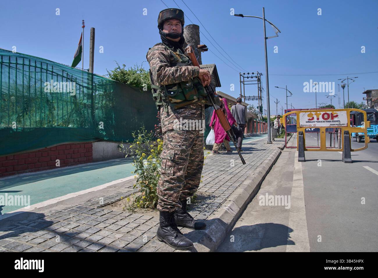 An Indian paramilitary soldier stands guard at a temporary checkpoint ...