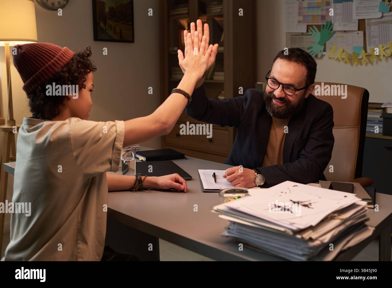 Happy school psychologist and his patient giving one another high five ...