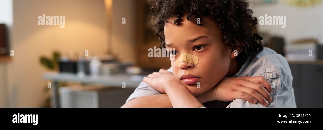 Header of sulky African American boy with bandage on nose sitting on ...