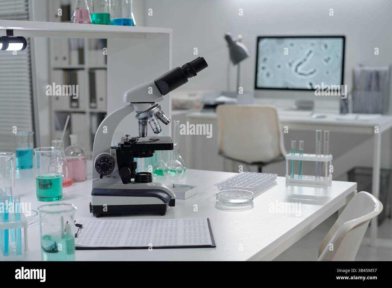 Modern laboratory setup featuring high-tech microscope and various chemical solutions on ...