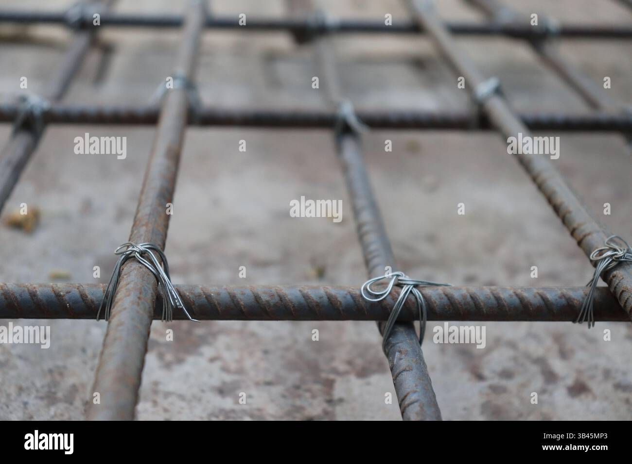 Focus on rusty rebar grid with wire ties on a cement foundation. Building construction and ...