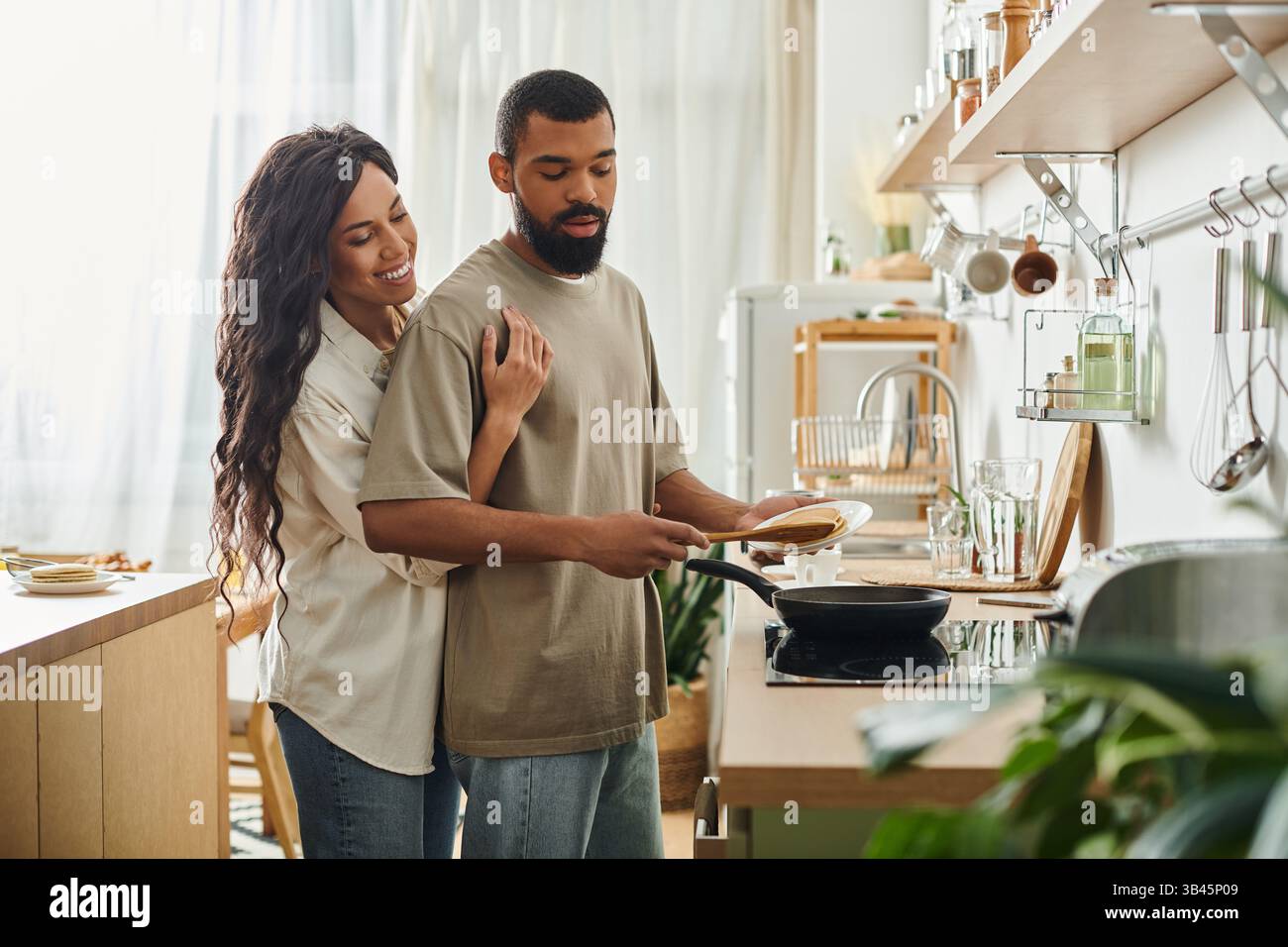 A joyful couple shares a tender moment while cooking together in their ...
