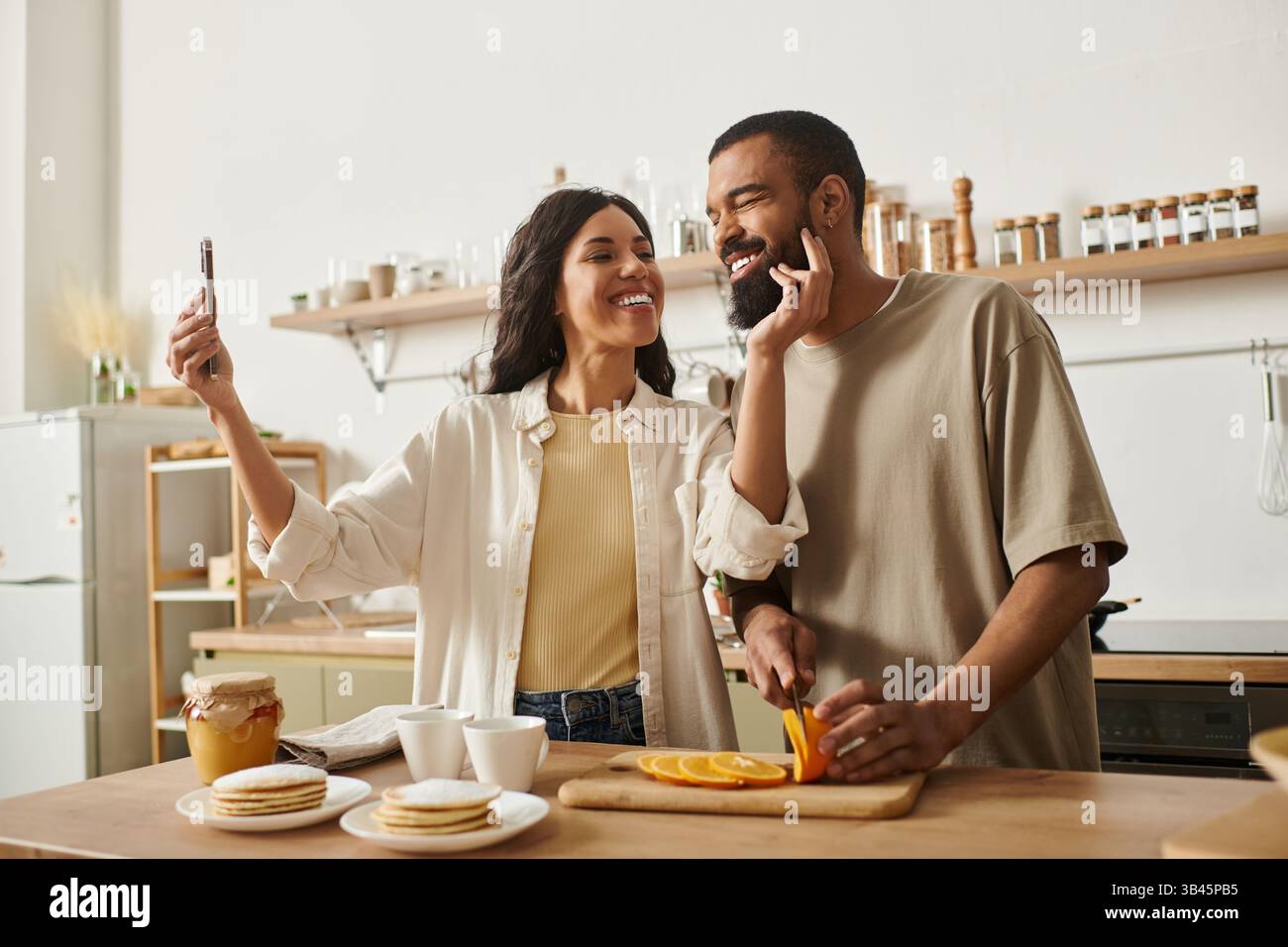 A couple shares smiles and laughter while cooking breakfast together at ...